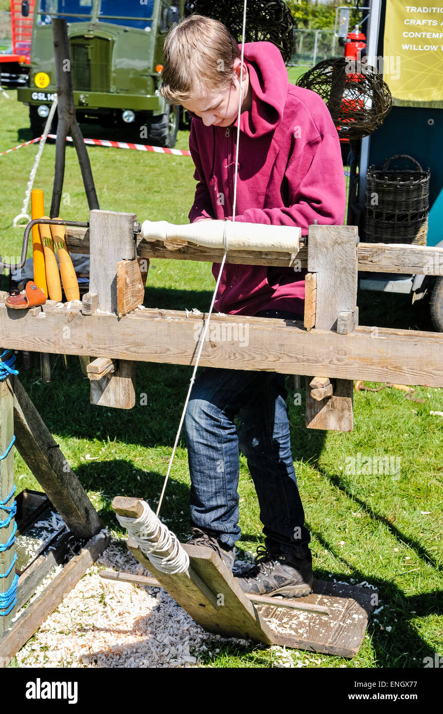 Young man uses a wood chisel and a foot operated lathe to turn wood ...