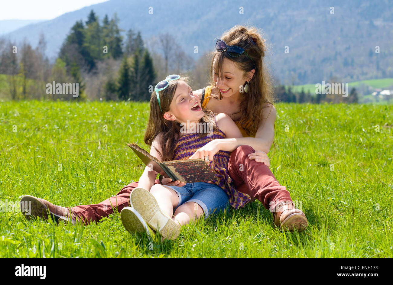 Mom and daughter reading a book in nature Stock Photo - Alamy