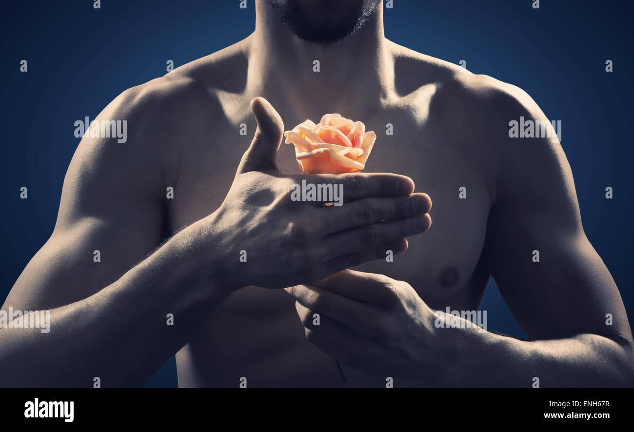 Strong and fit man holding an orange rose Stock Photo - Alamy