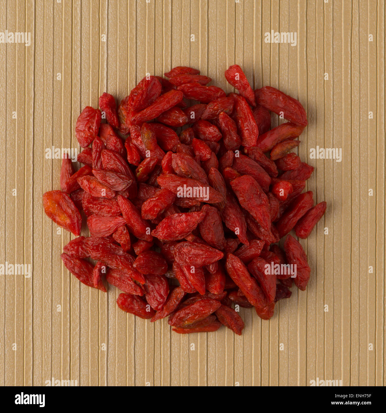 Top view of circle of dry red goji berries against yellow vinyl ...
