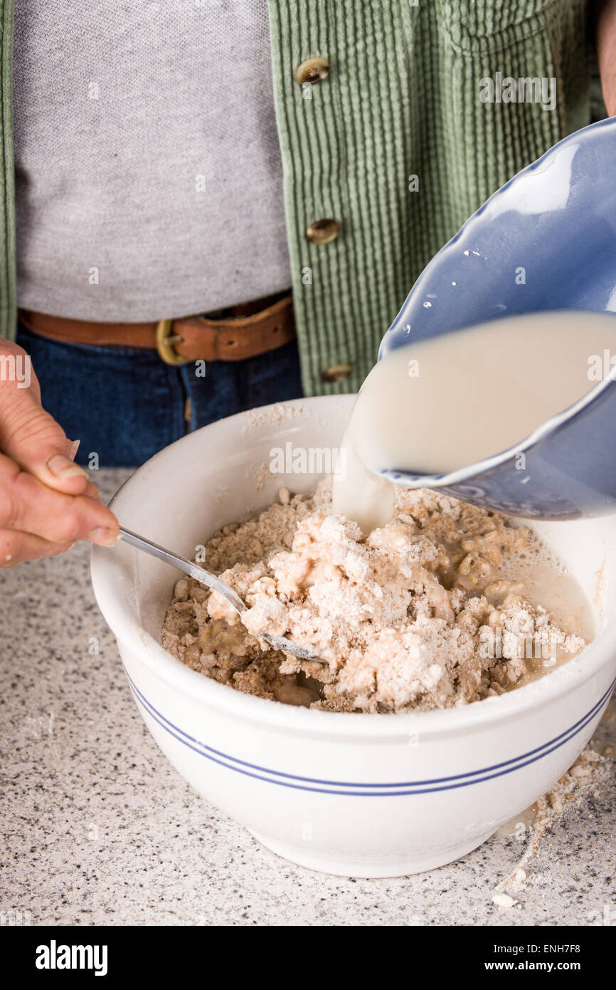 Pouring activated yeast mixture into a mixing bowl of other bread ...
