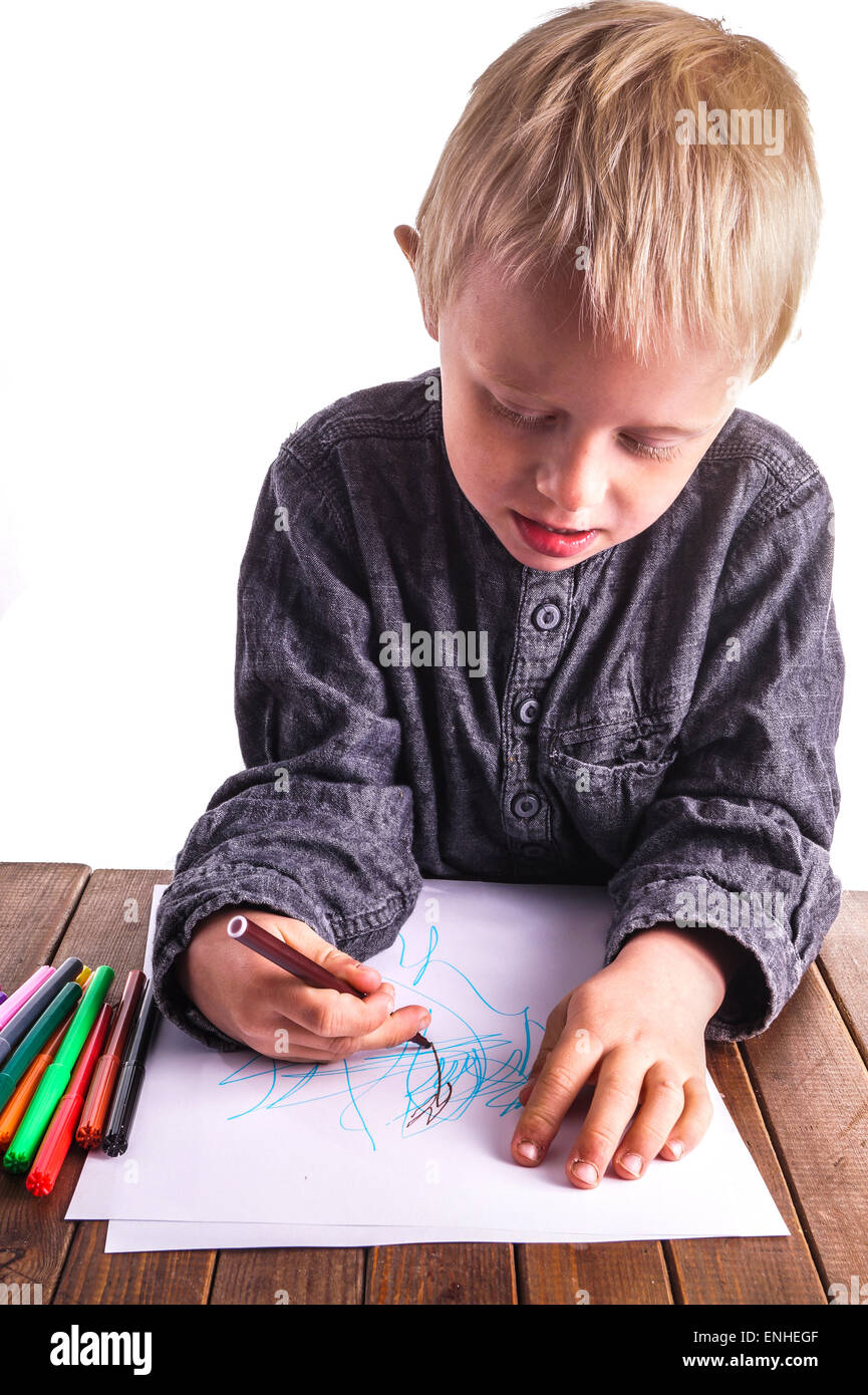 Little boy draws a drawing. He has many markers and are very focused on ...