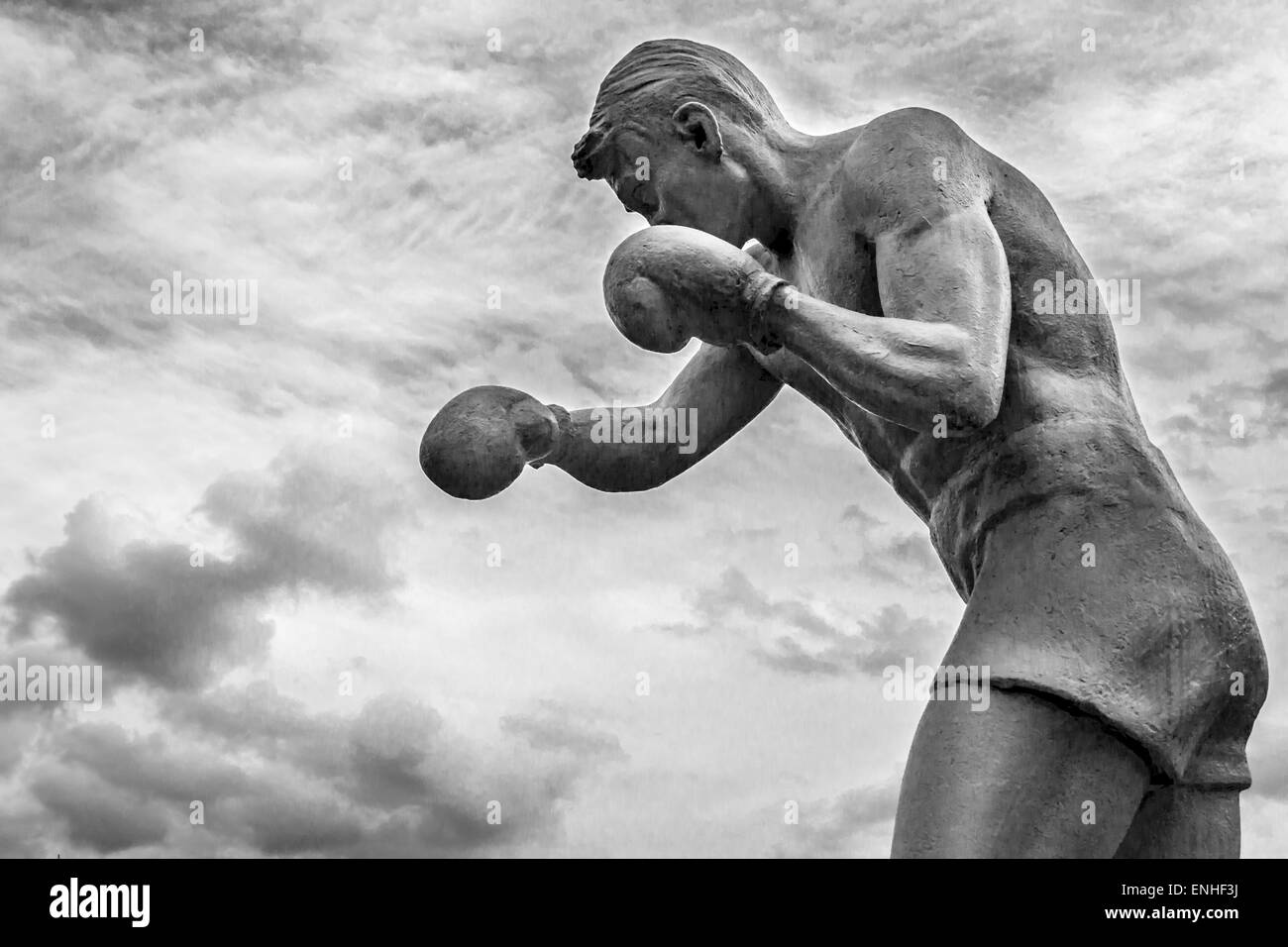 Male statue boxer with gloves throwing punches at clouds in monochrome ...