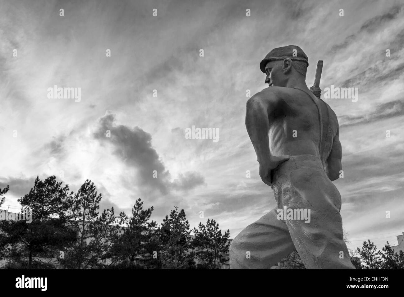 Modern industrial man in statue form striding towards the clouds in ...
