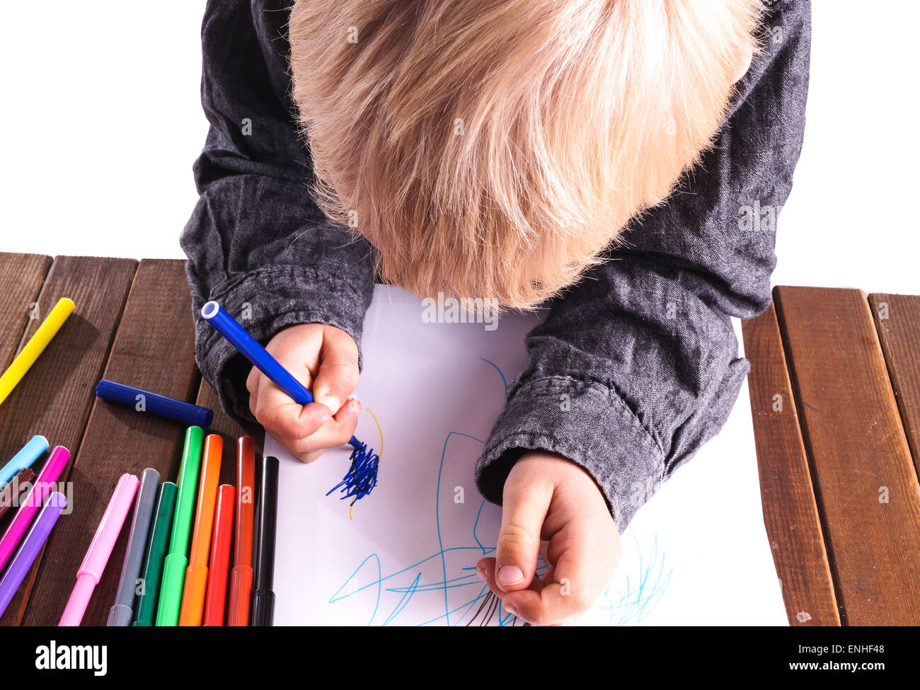 Little boy draws a drawing. He has many markers and are very focused on ...