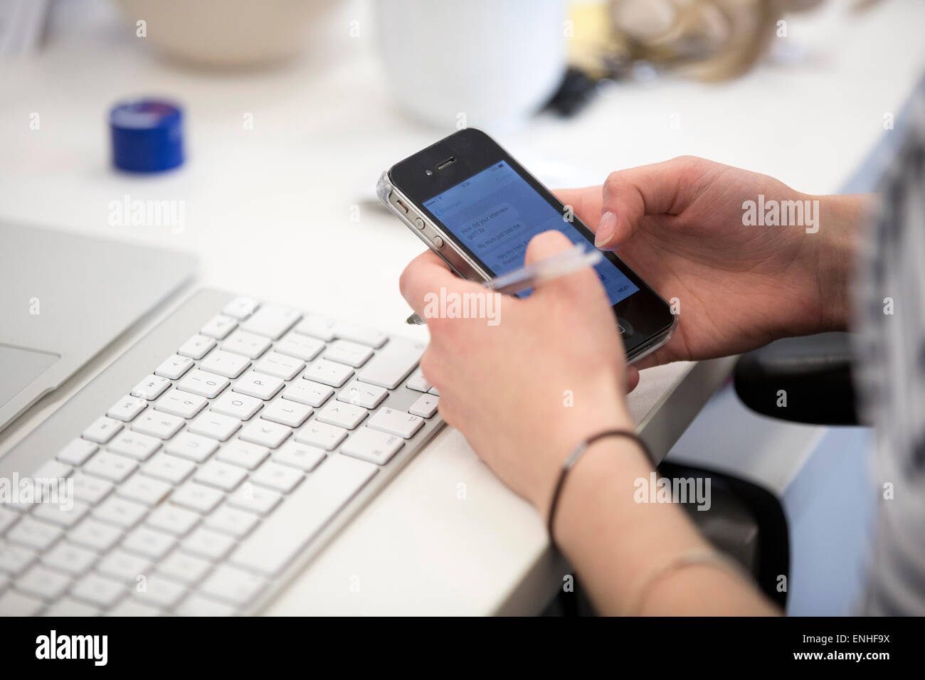 woman's hands texting on iphone sat at office desk Stock Photo - Alamy