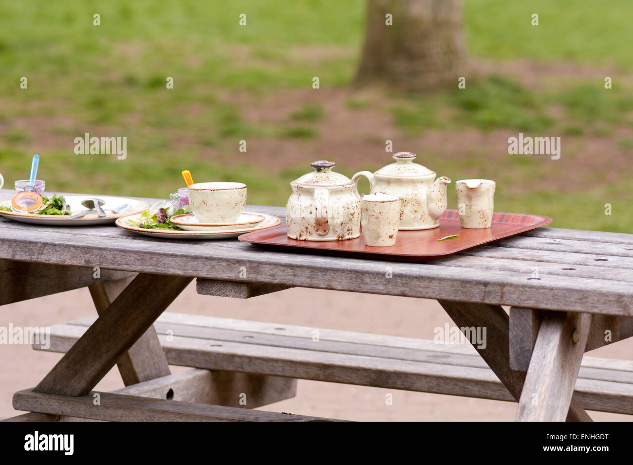 Tea cups and plates on wooden bench style table at cafe Stock Photo - Alamy