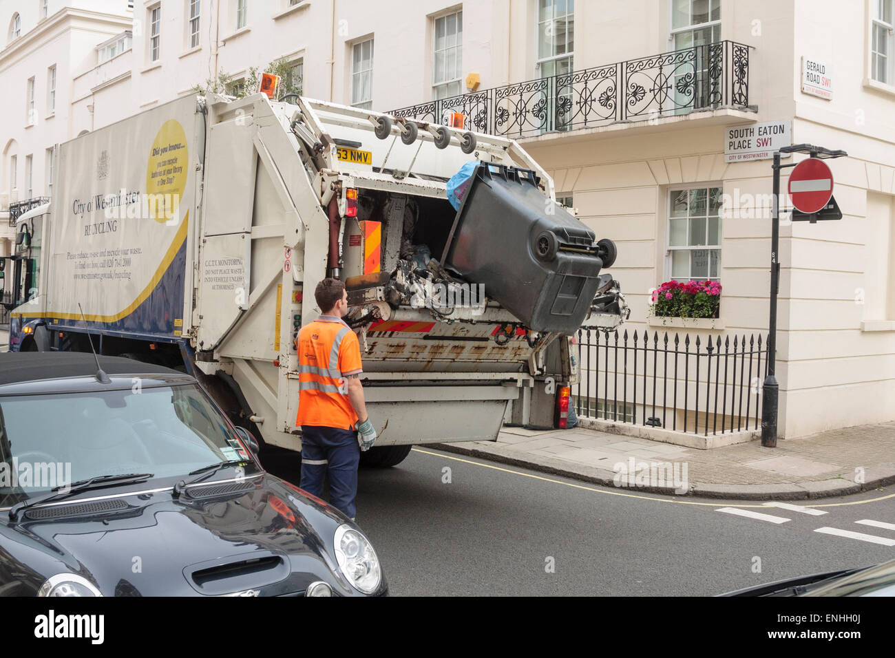 A binman supervises the back of a dustcart during rubbish collection in ...