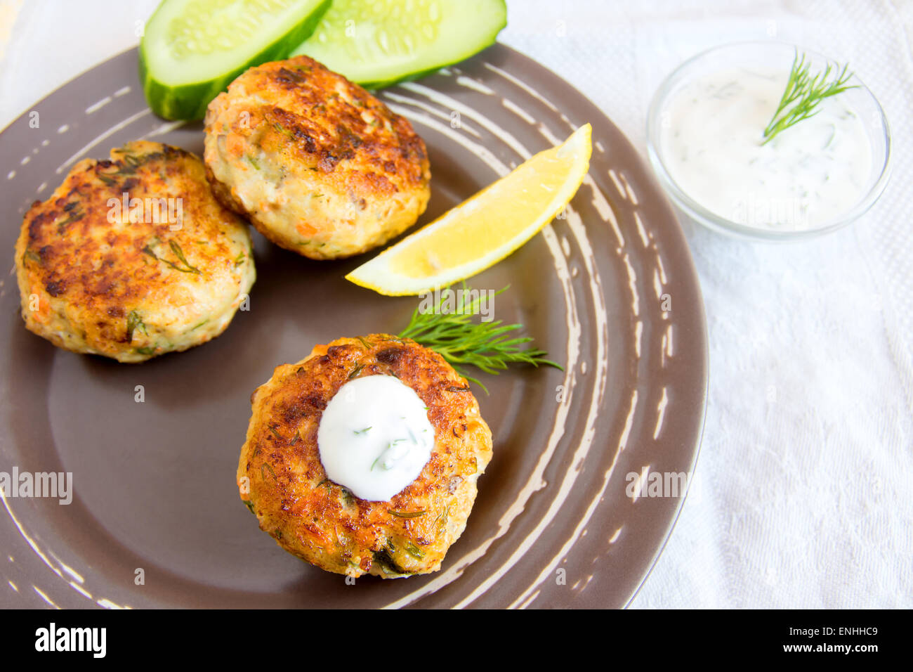 Homemade thai fish cakes with white sauce, dill and lemon on plate ...