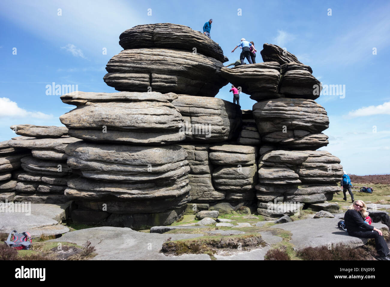 Walkers climbing wind eroded Gritstone rocks named The Wheel Stones on ...