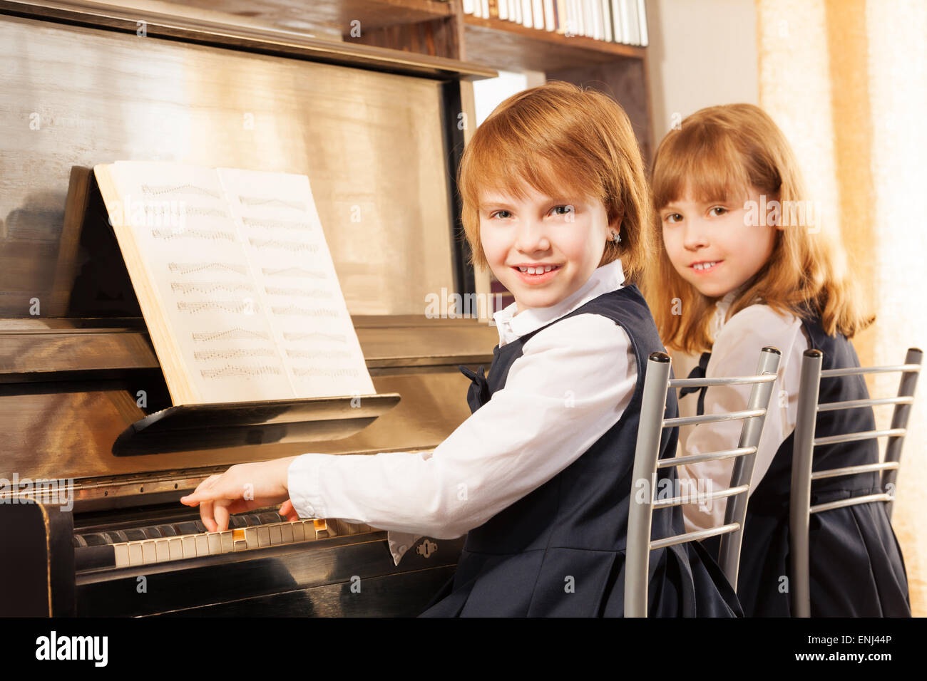 Cheerful beautiful small girls play piano together Stock Photo - Alamy