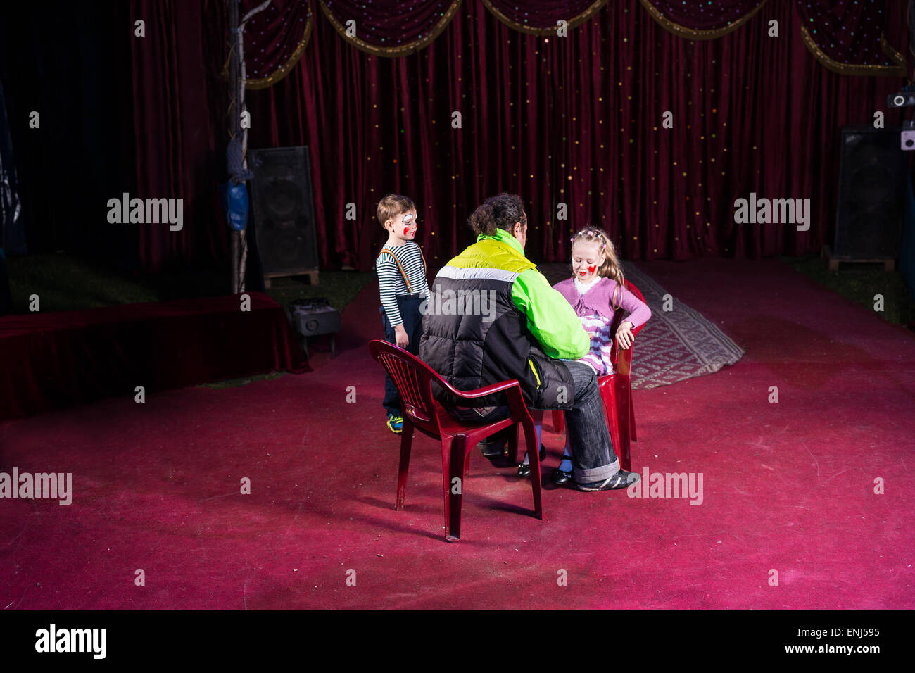Man Applying Make Up to Faces of Young Boy and Girl on Empty Stage ...