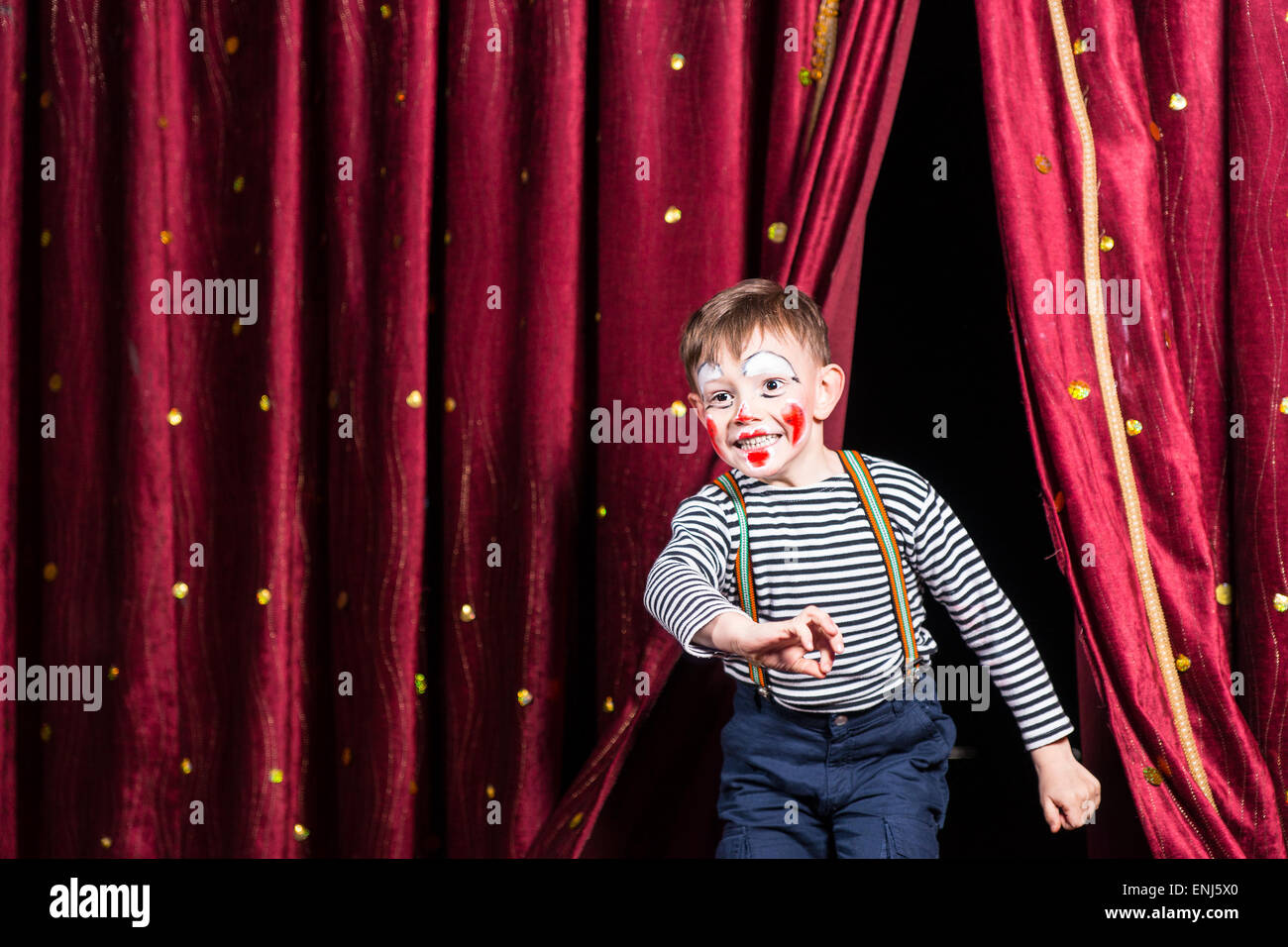 Happy little boy actor making his entrance onto the stage from between ...