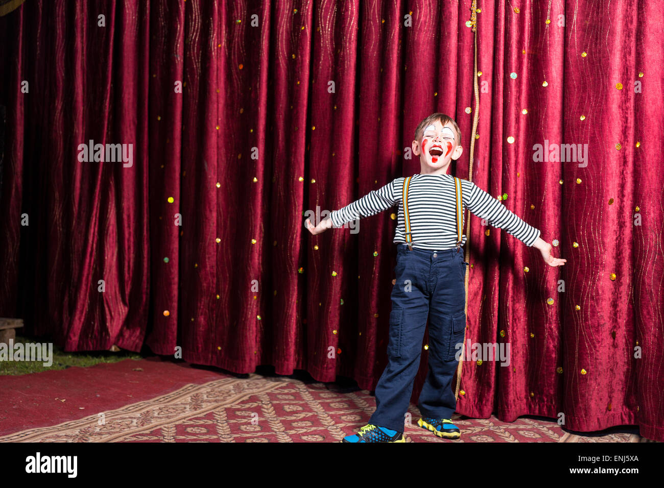 Adorable little boy singing on stage during a play standing with ...