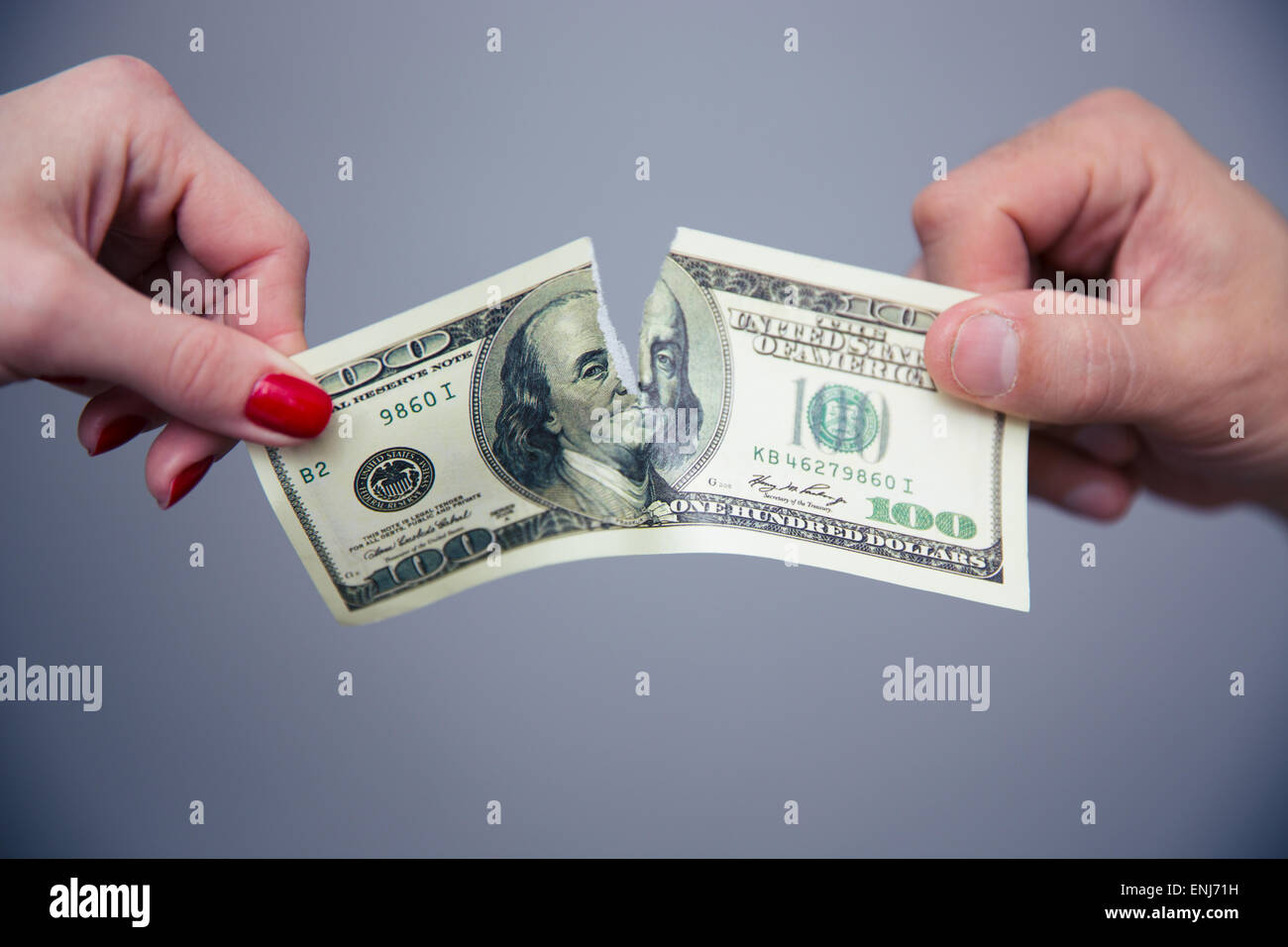 Concept image of a female and male hand dividing money over gray ...