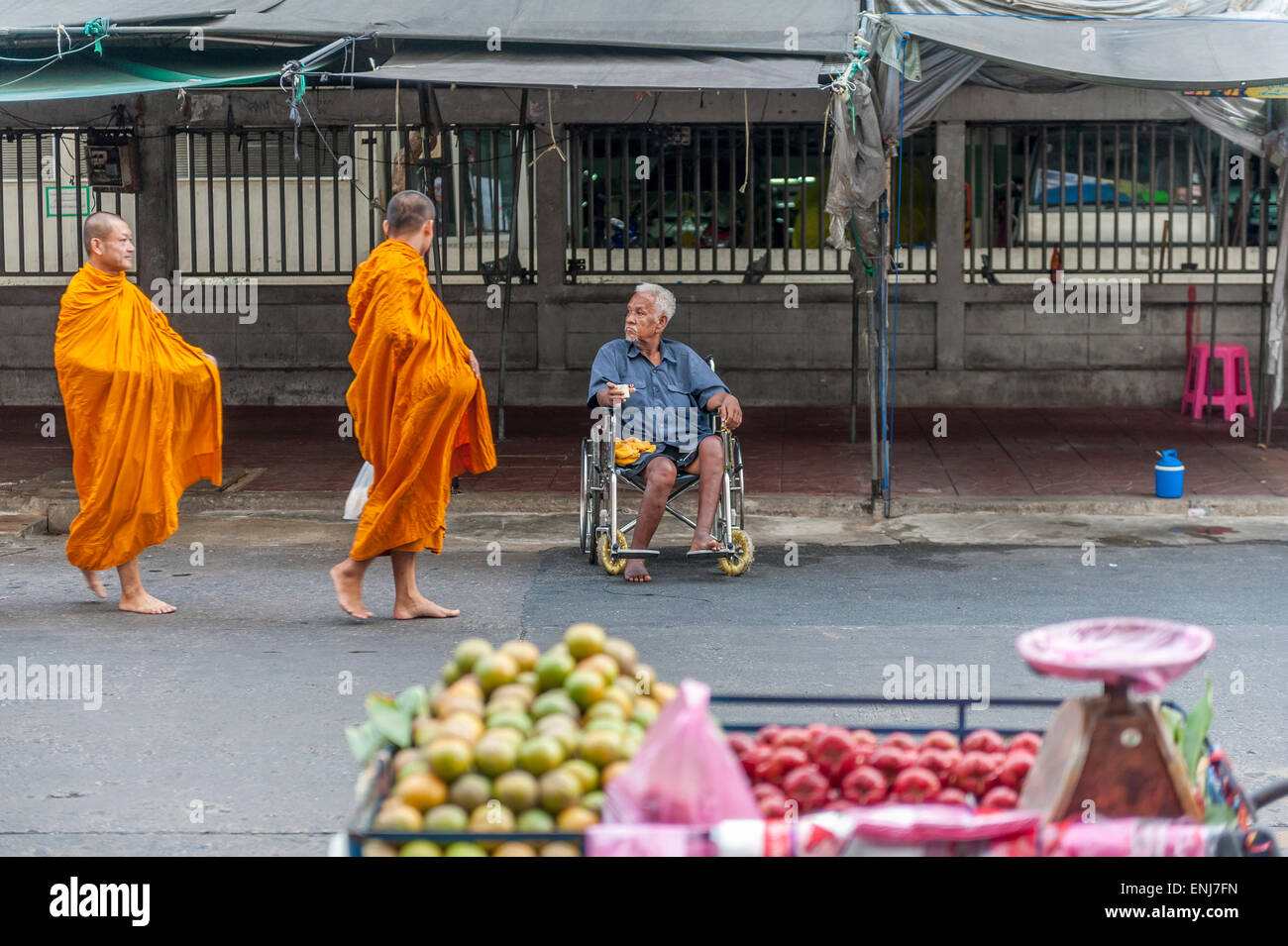 A wheelchair bound begger watches a group of Buddhist monks on their ...