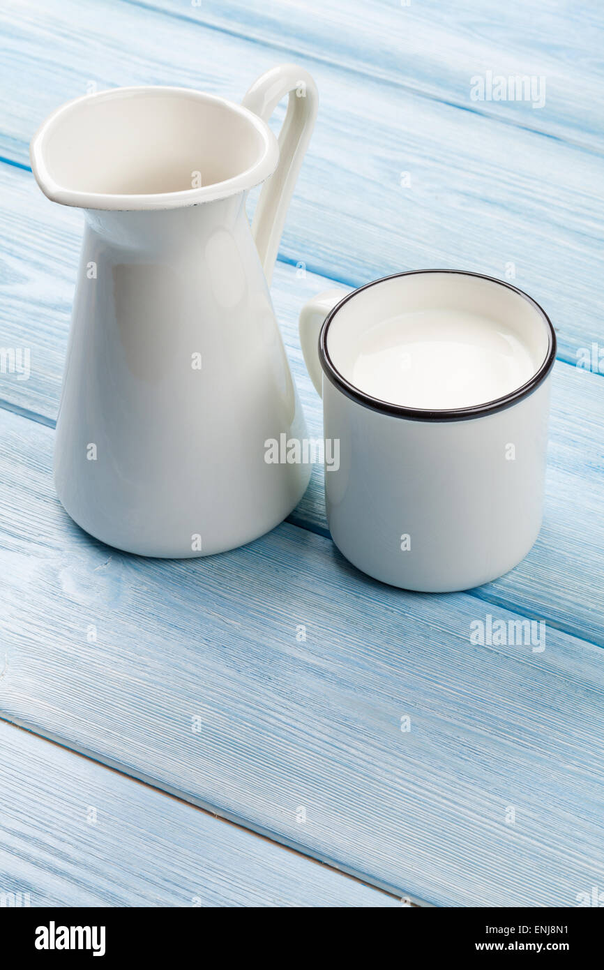 Milk cup and pitcher on wooden table Stock Photo - Alamy