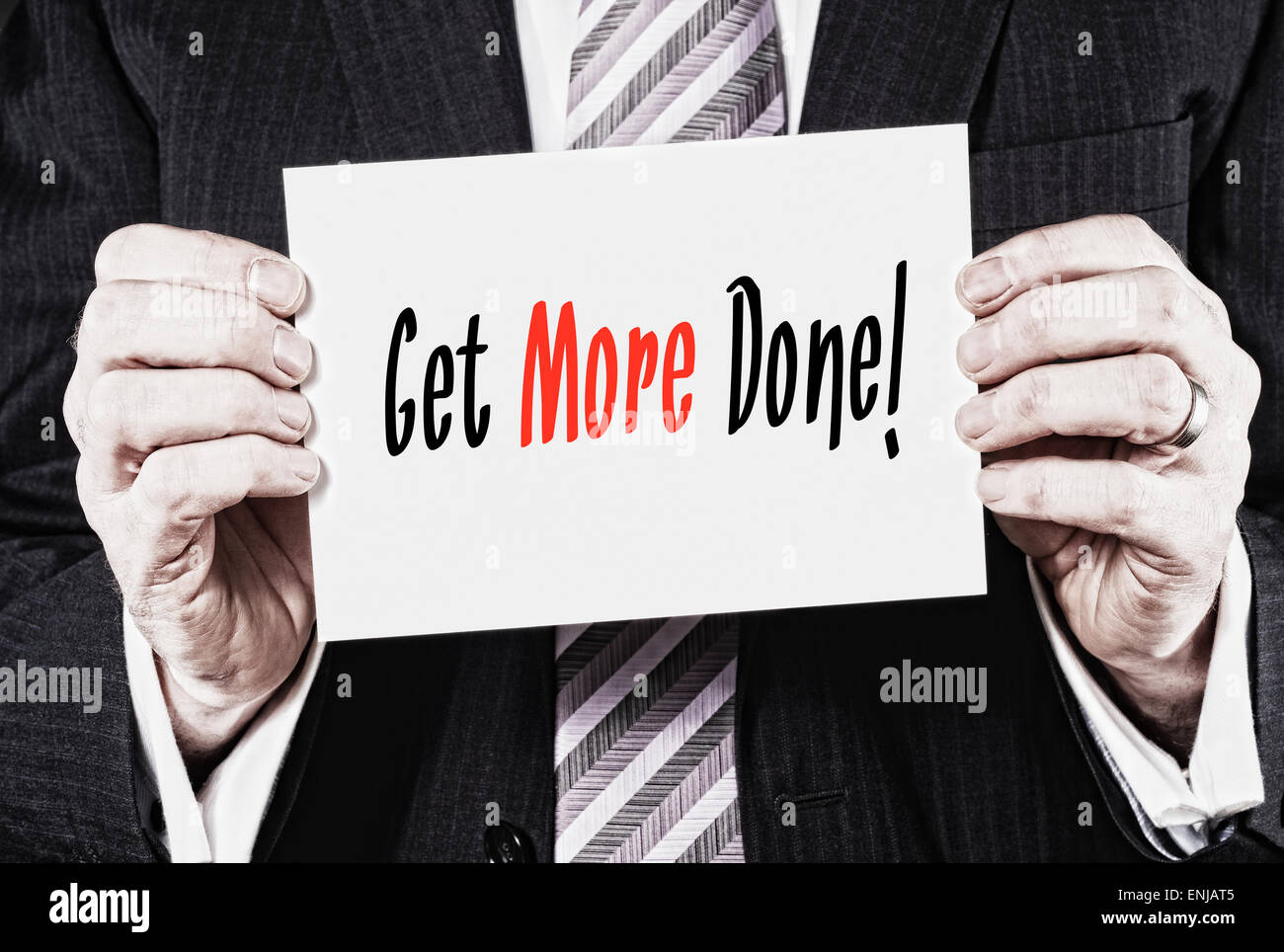 A businessman holding a card with the words, Get More Done, written on ...
