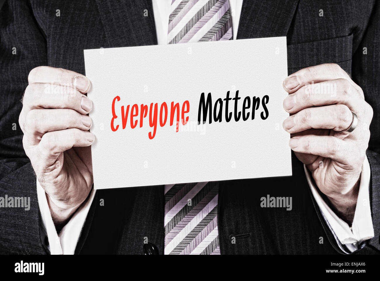 A businessman holding a card with the words, Everyone Matters written ...