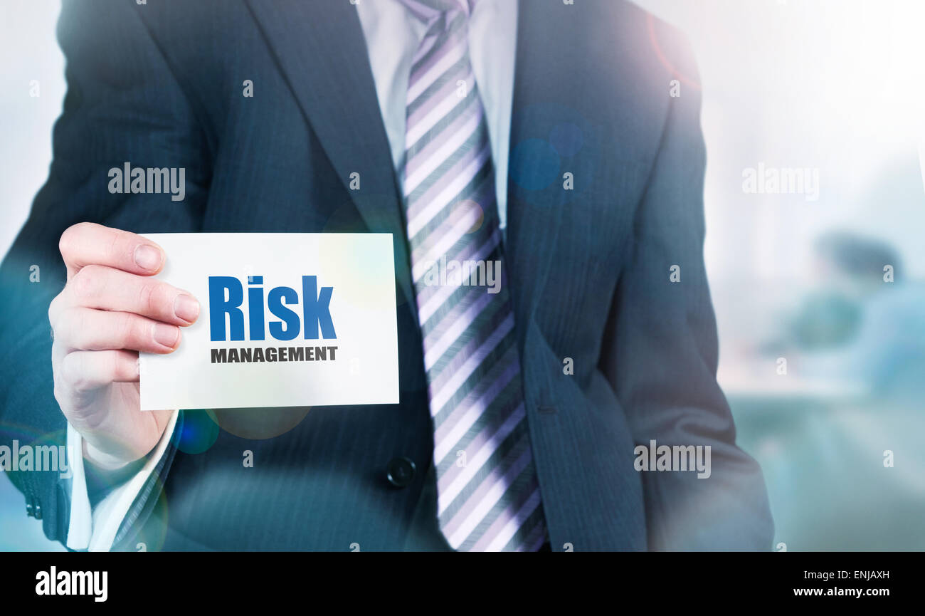 A businessman holding a card with the words, Risk Management, written ...