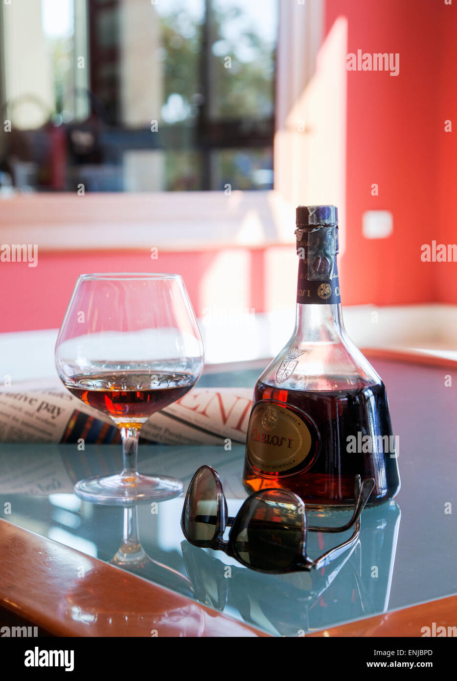 Still life of a Hennessy cognac bottle on a table, a pair of sun ...