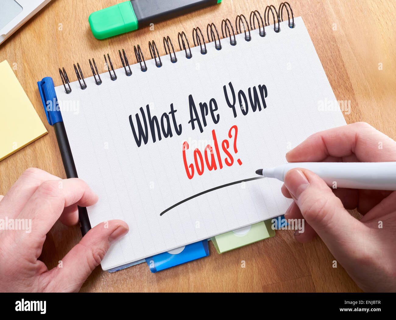 A businessman writing the words, What Are Your Goals, on a note pad ...