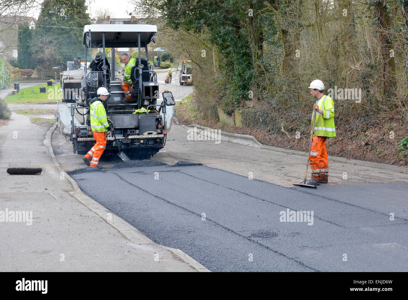 Men working at road works resurfacing & repairs using mechanical tarmac ...