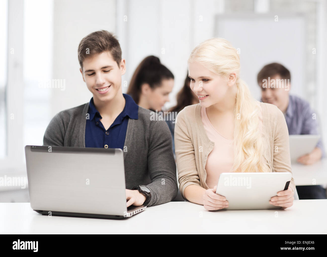 two smiling students with laptop and tablet pc Stock Photo - Alamy