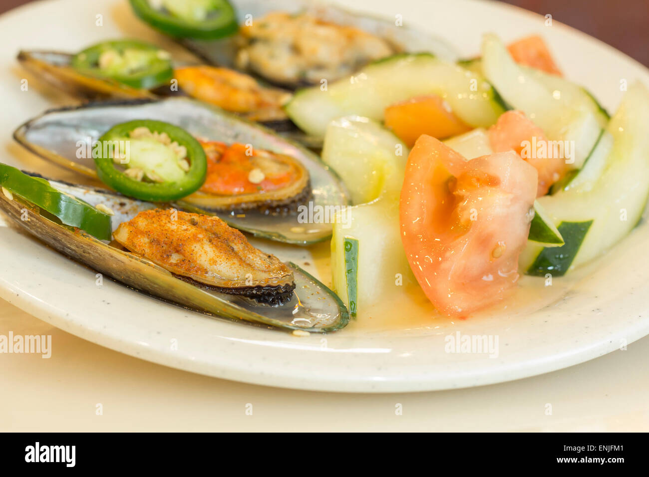 Spicy chili mussels with jalapeno slices and cucumber tomato salad ...