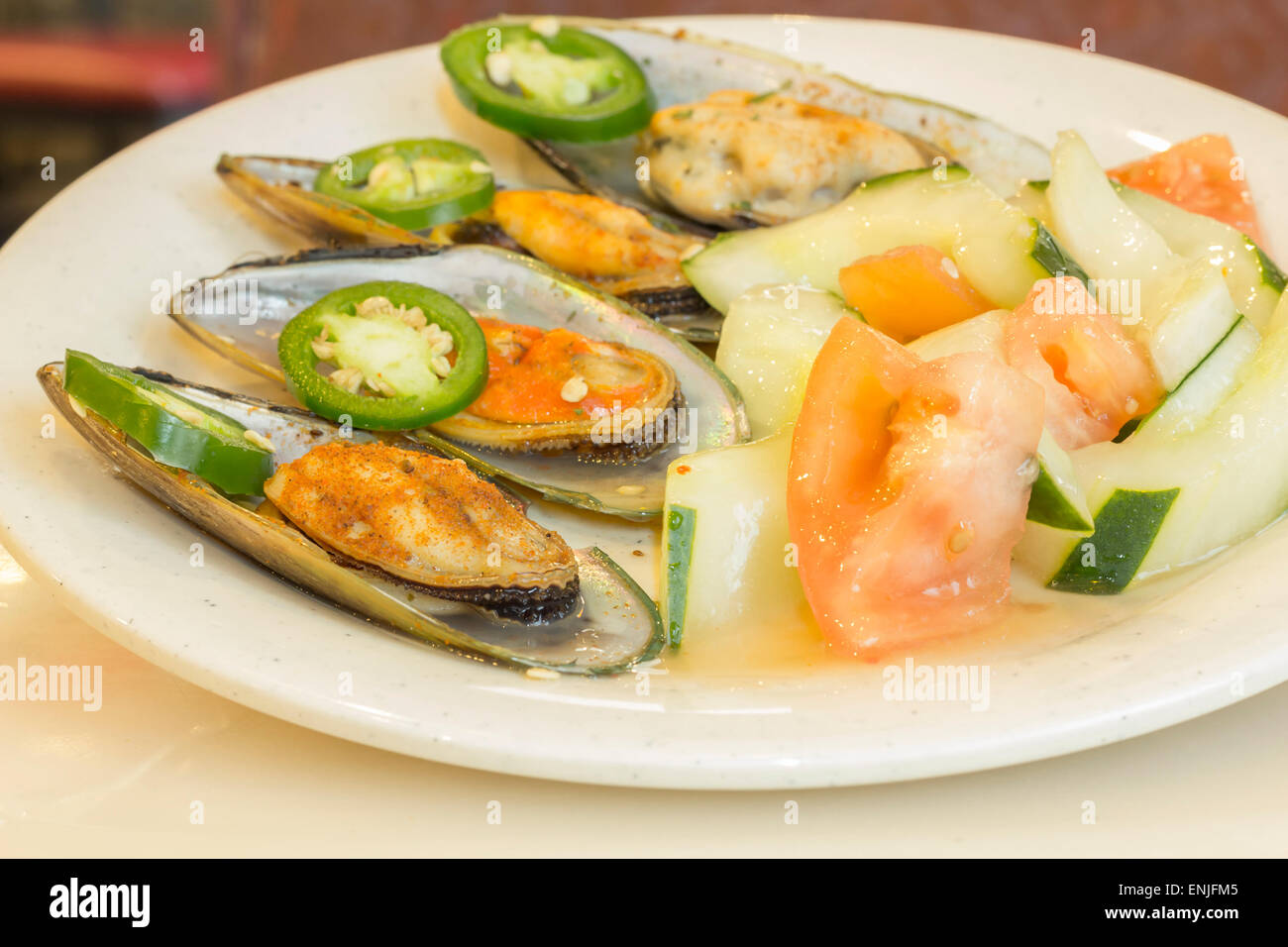 Spicy chili mussels with jalapeno slices and cucumber tomato salad ...