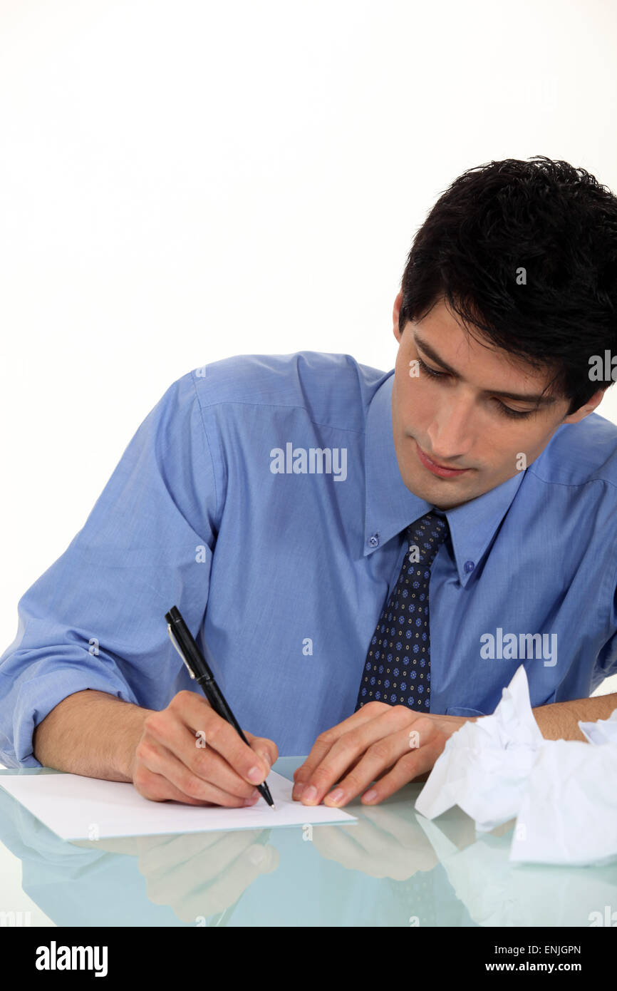Frustrated man writing at desk Stock Photo - Alamy