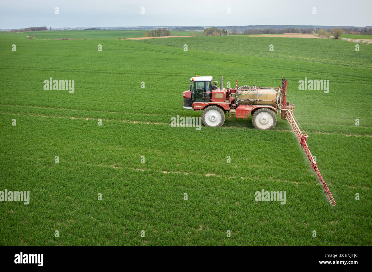 Aerial view of the tractor spraying the chemicals on the large green ...