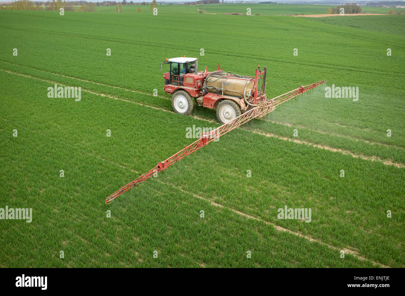 Aerial view of the tractor spraying the chemicals on the large green ...