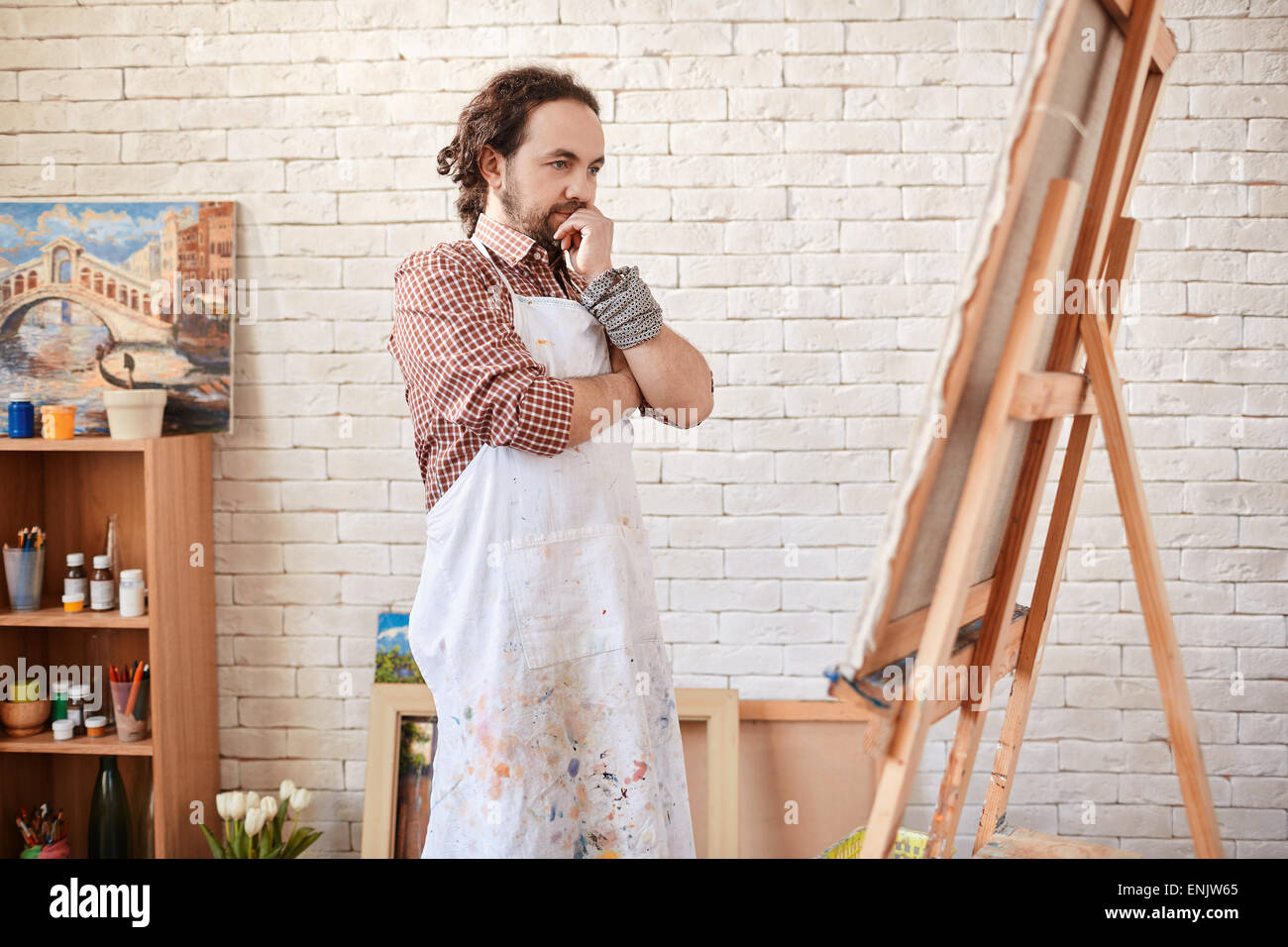 Young artist looking at canvas in studio Stock Photo - Alamy