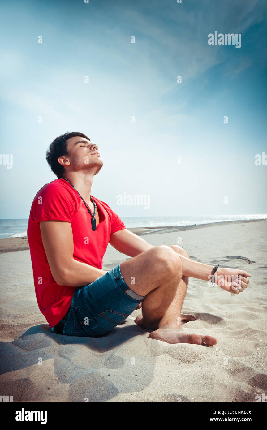 man in red shirt sitting on the beach Stock Photo - Alamy