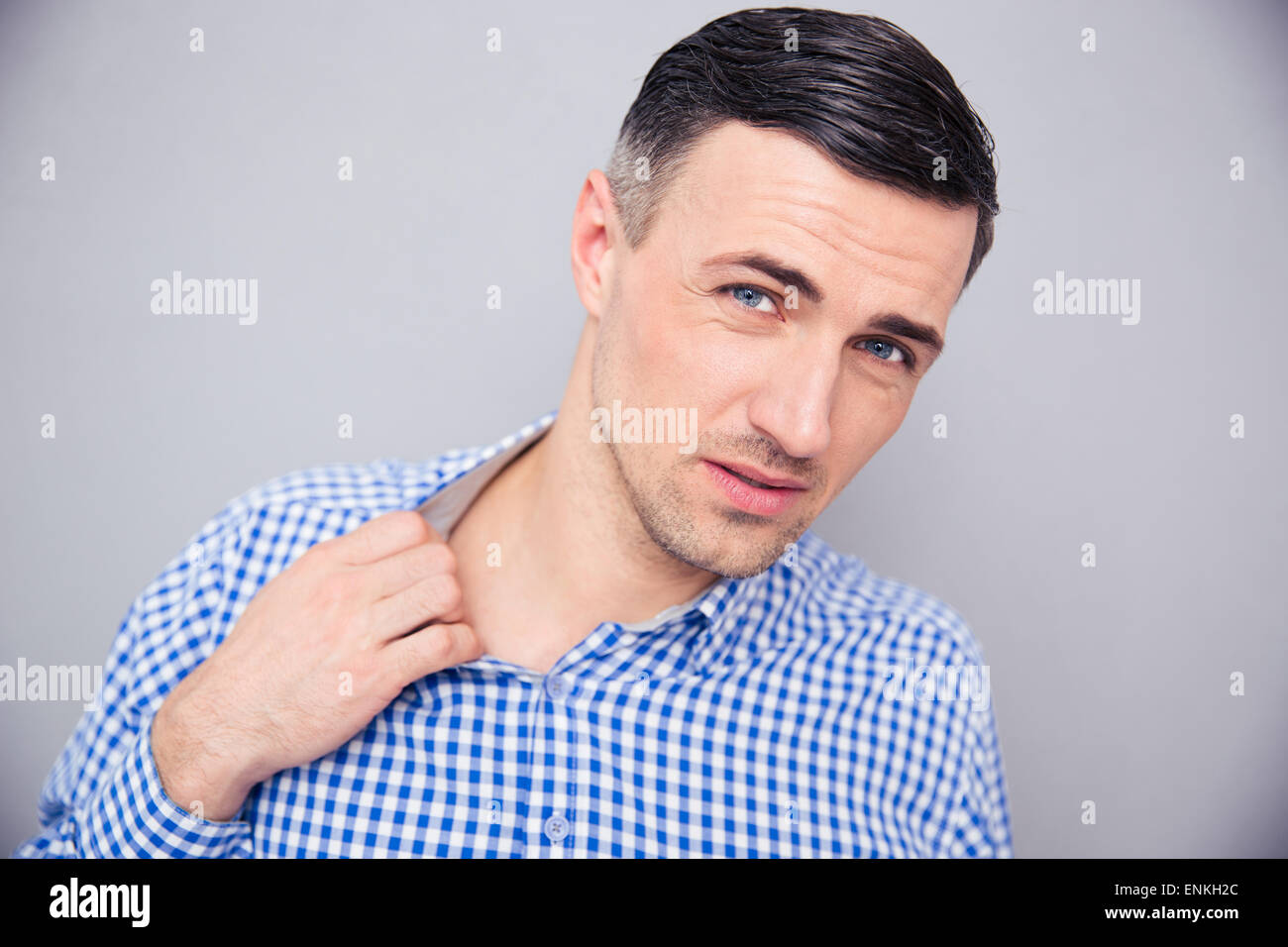 Man loosing his shirt to relax a bit after hard work over gray ...