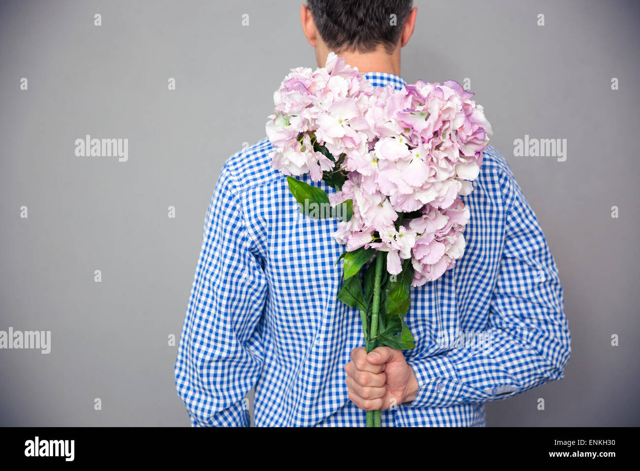 Back view portrait of a man standing with flowers over gray background ...