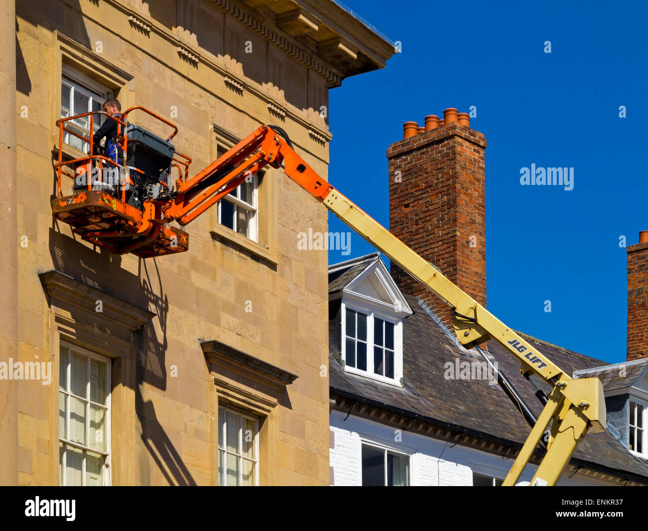 Man using a cherry picker crane to work on a high level platform on a ...