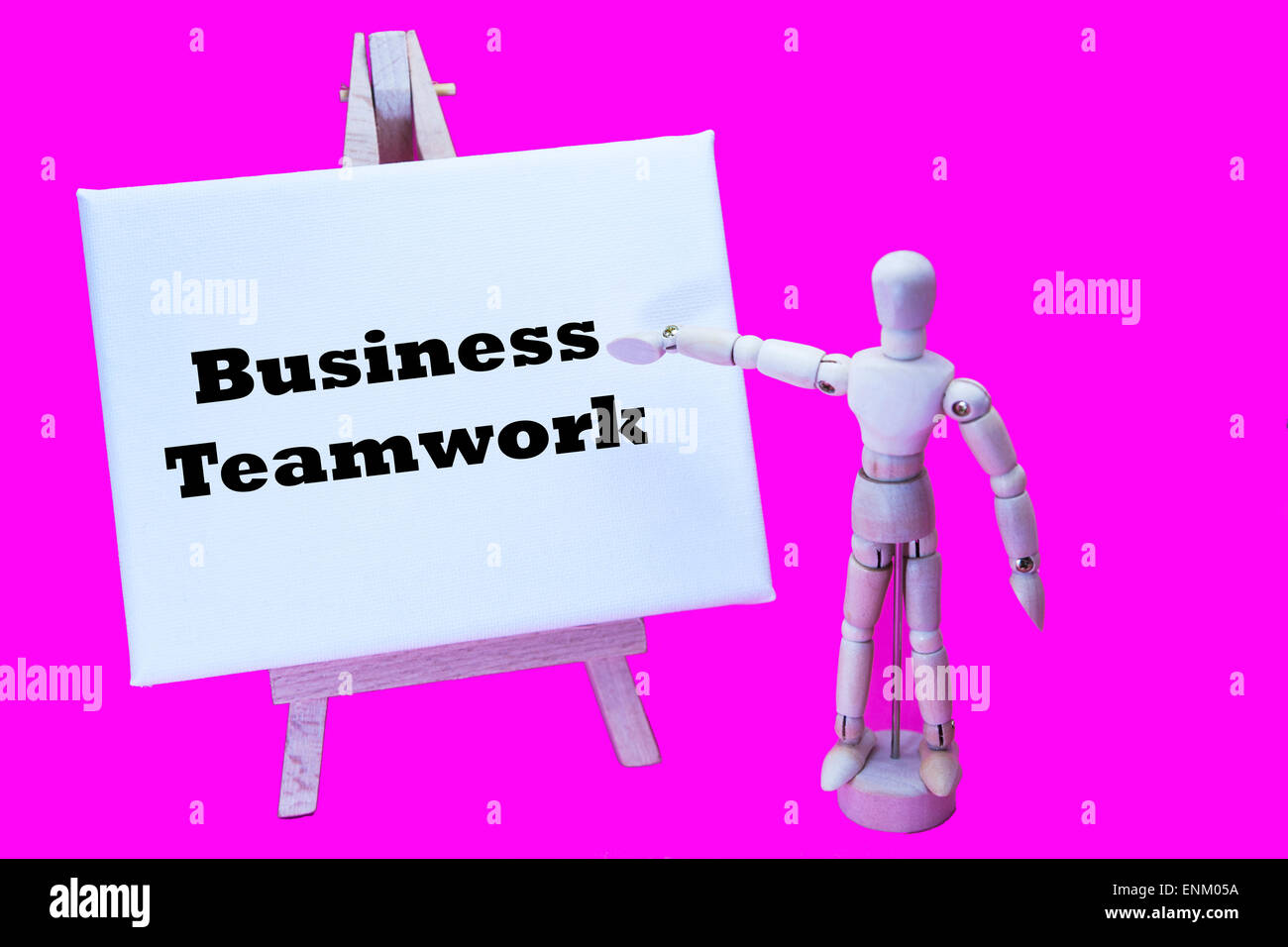 Wooden man with white board pointing at words "Business Teamwork ...