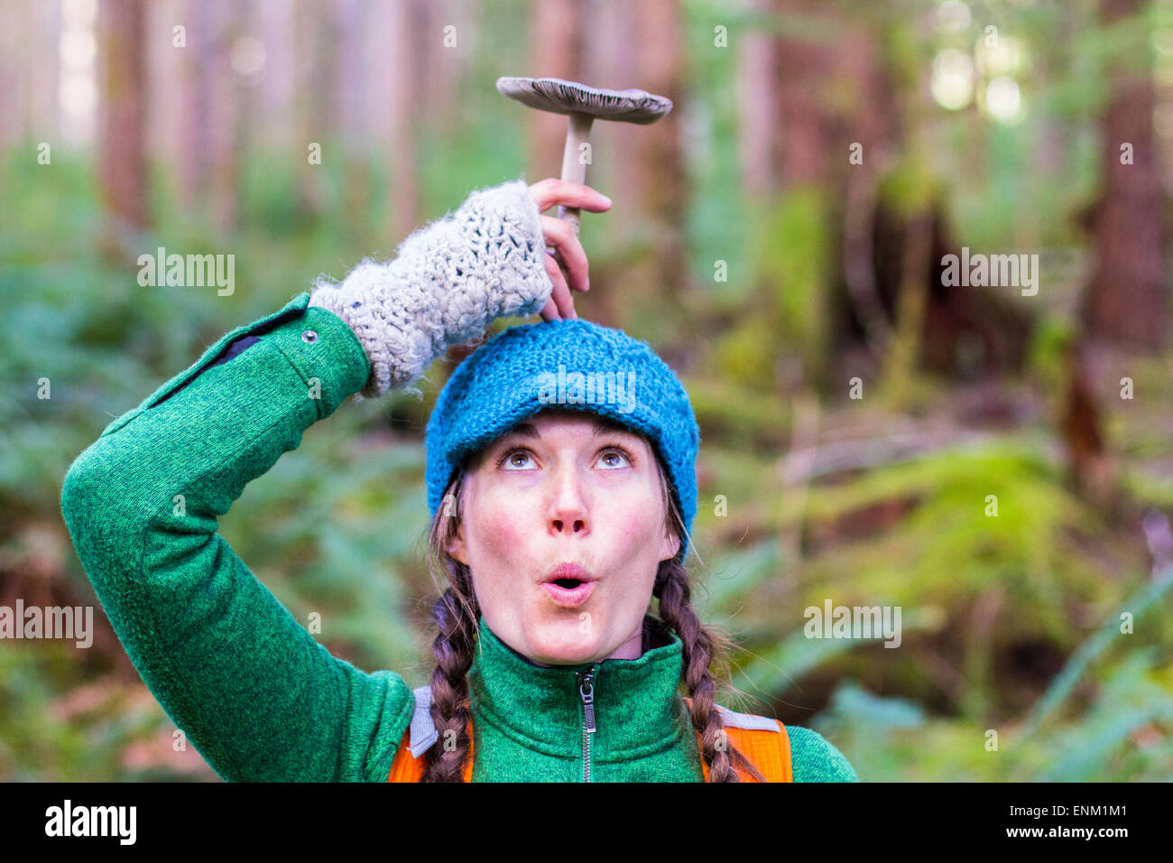 Woman makes a silly face while holding a mushroom on her head in the ...