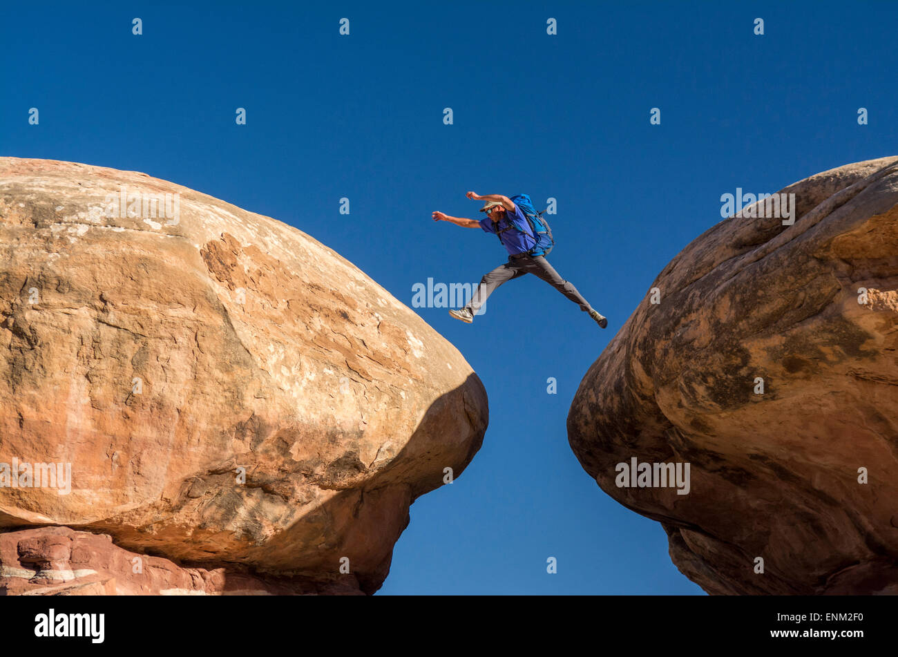 A man jumping between two rocks, Needles District of Canyonlands ...