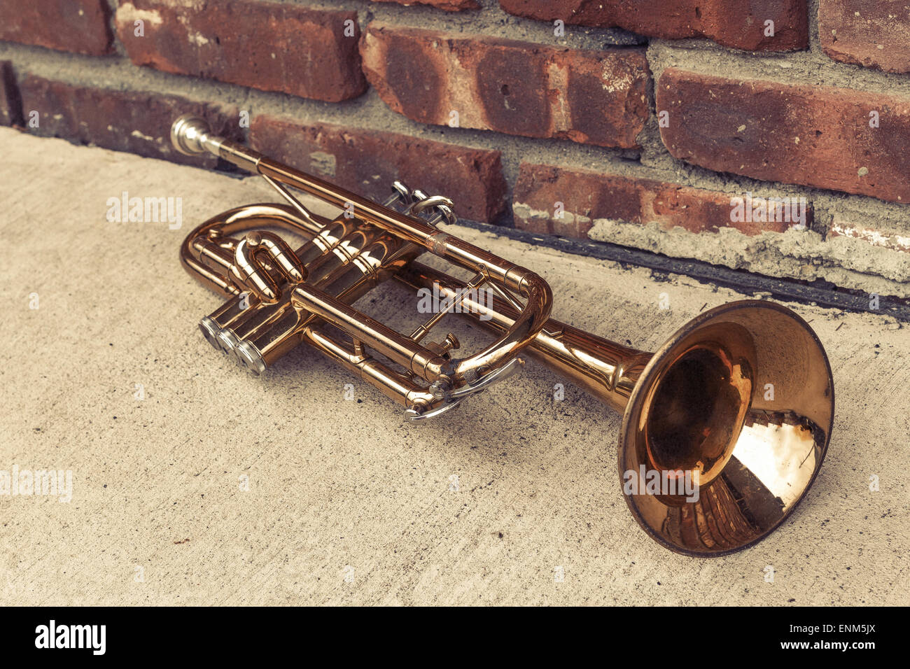 Old worn trumpet stands alone against a brick wall outside a jazz club ...