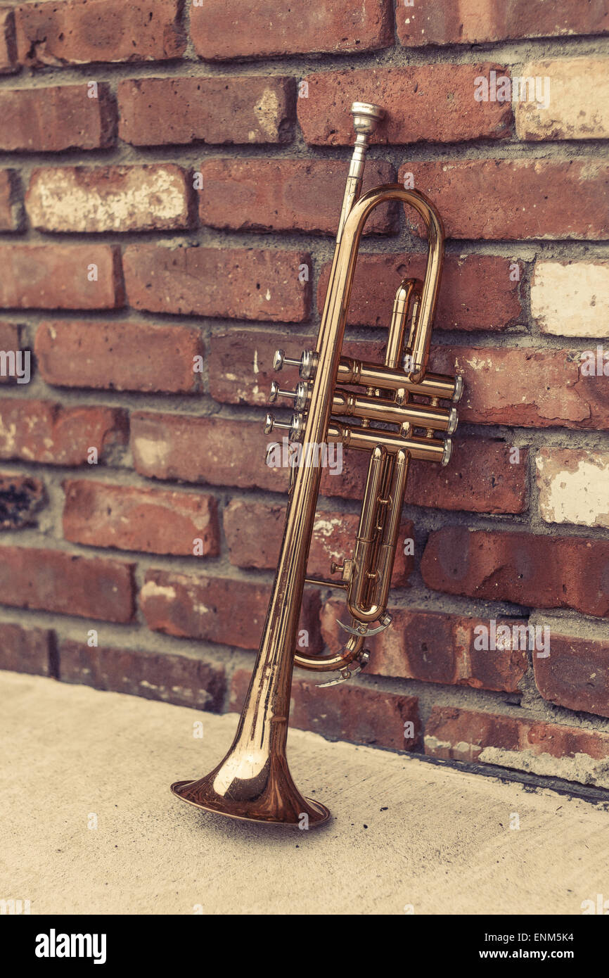 Old worn trumpet stands alone against a brick wall outside a jazz club ...