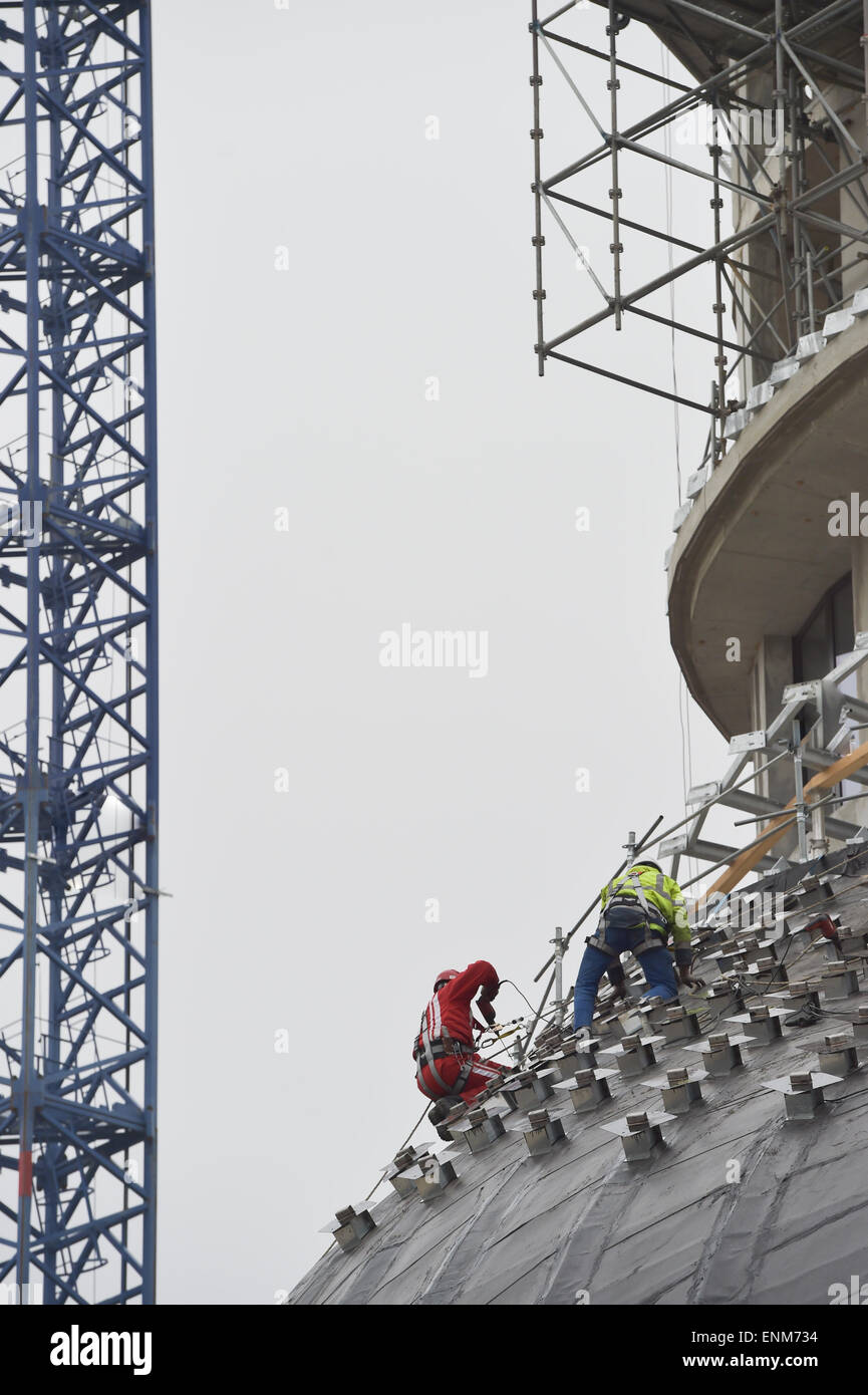 Worker using safety strap on the roof of a bulding under construction ...