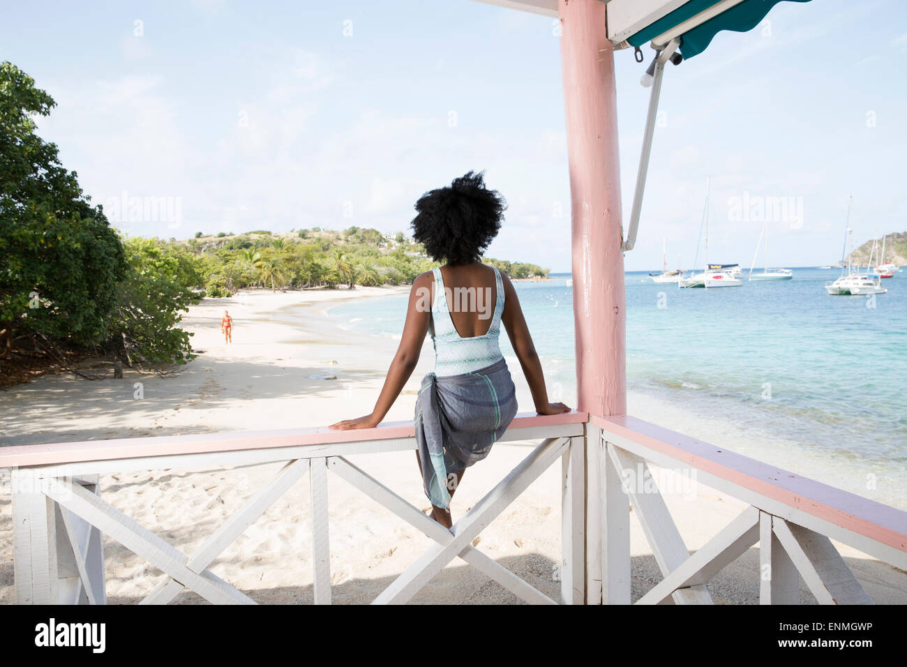 Young black woman sitting on veranda at beach, rear view Stock Photo ...