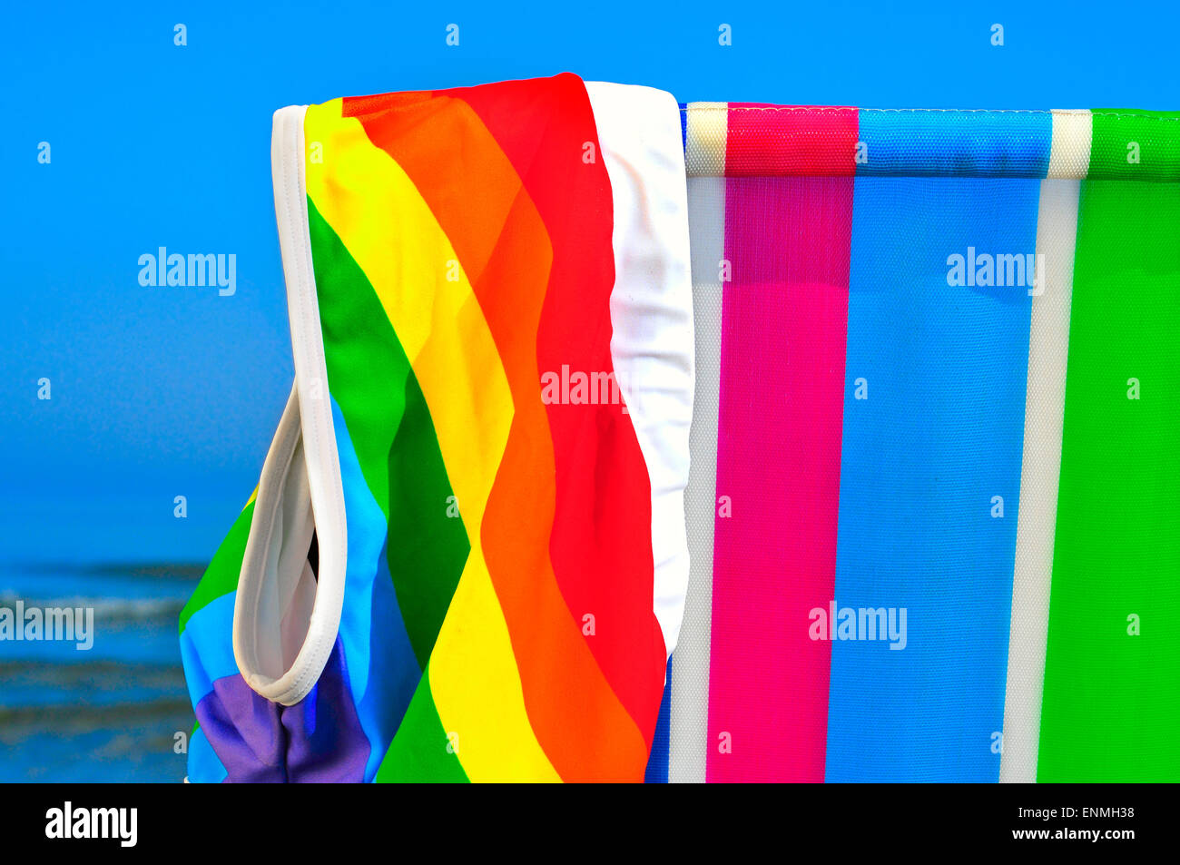a swimsuit patterned with the rainbow flag on a deck chair of different ...
