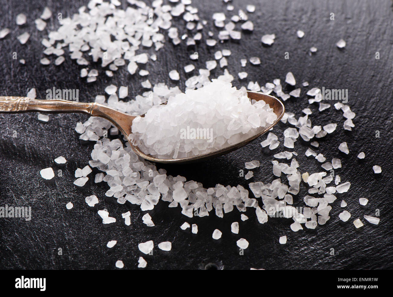 Salt in a spoon on black background. Selective focus Stock Photo - Alamy