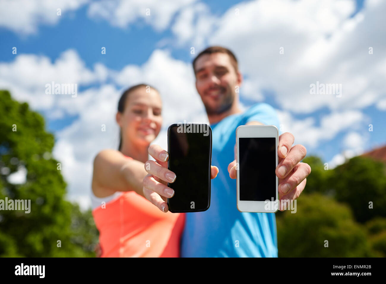 two smiling people with smartphones outdoors Stock Photo - Alamy