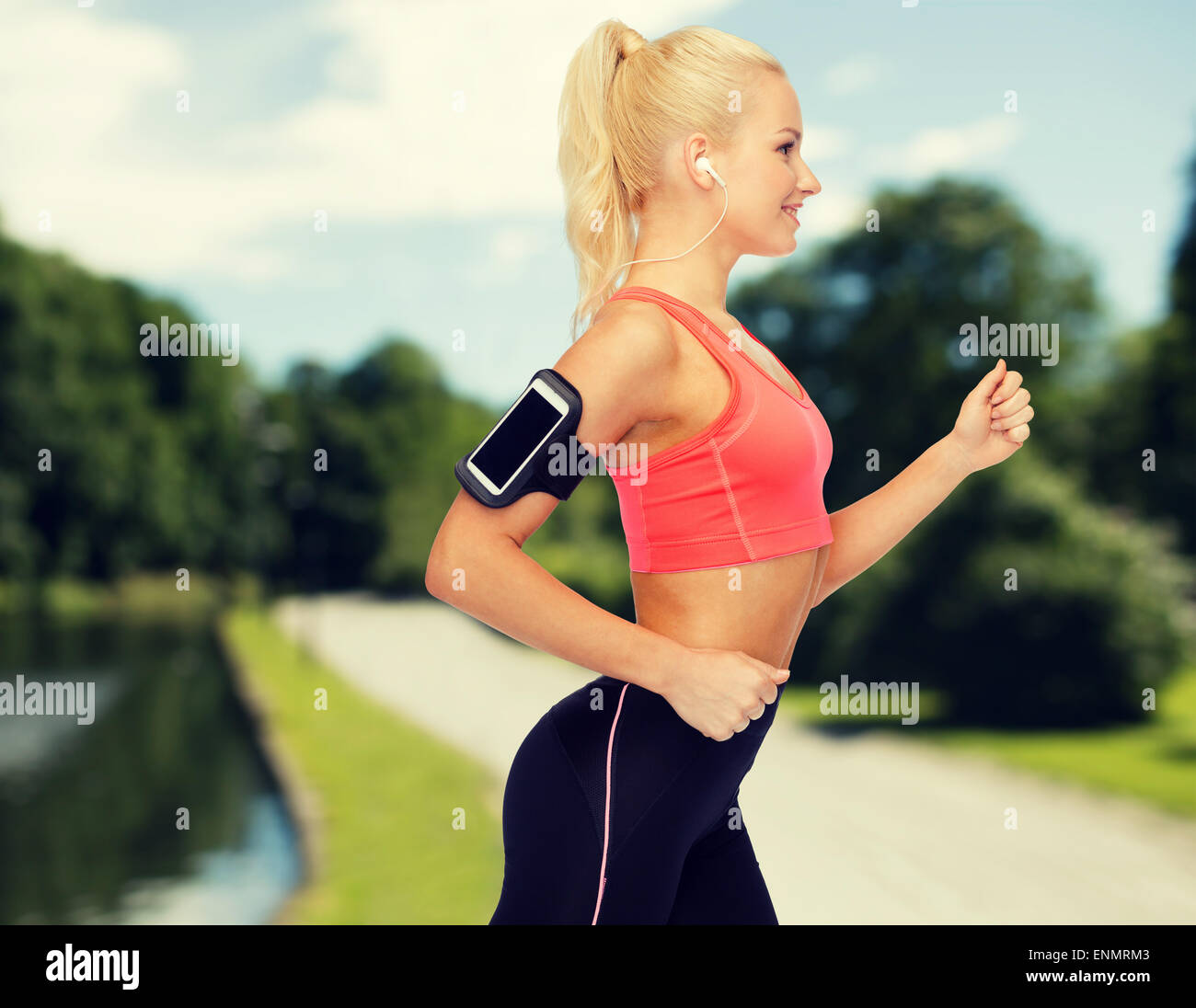 sporty woman running with smartphone and earphones Stock Photo - Alamy