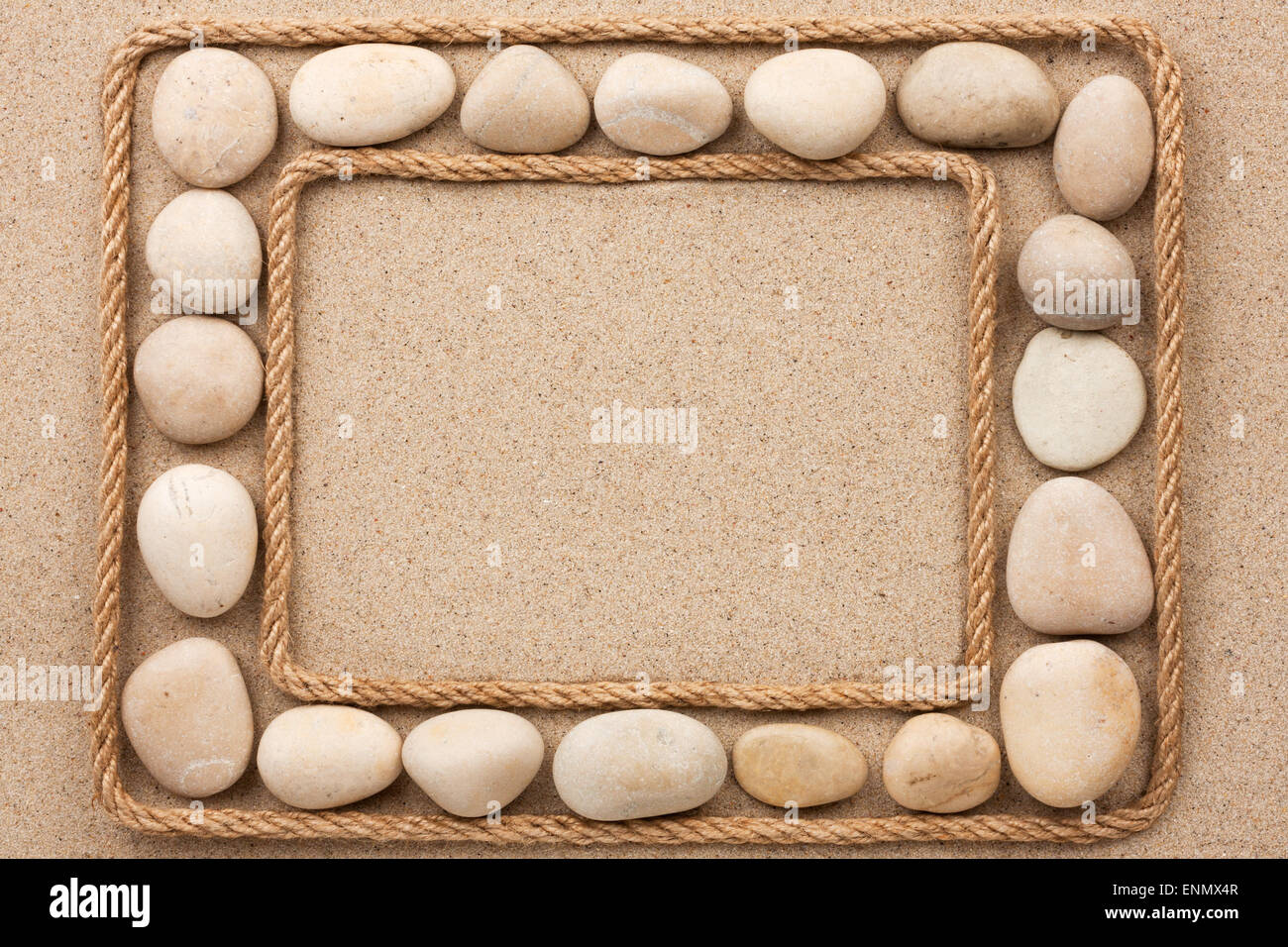 Beautiful frame with rope and white stones on sand, as a background ...